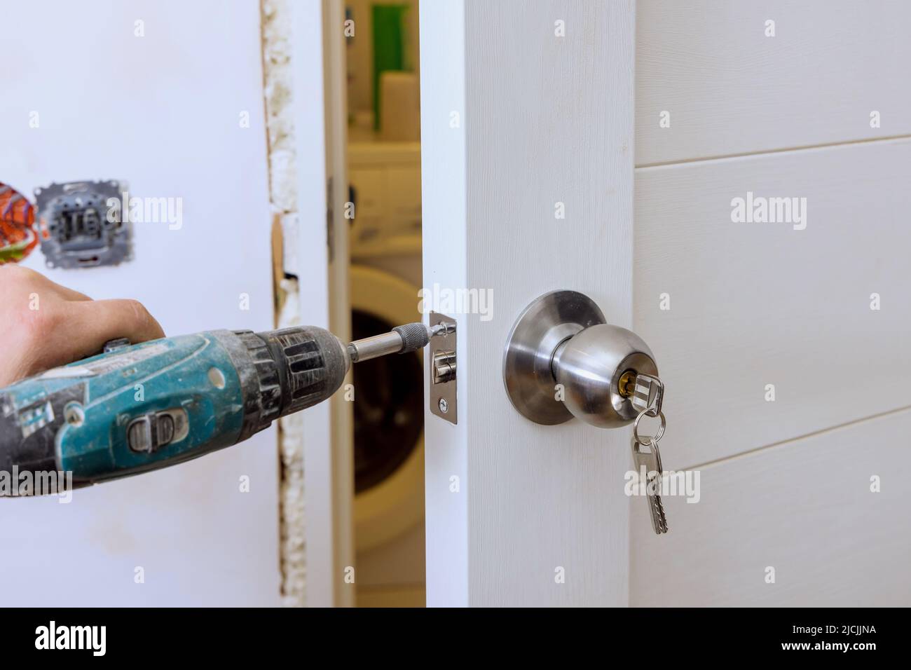 Builder in installing a door lock the door of a new house Stock Photo ...
