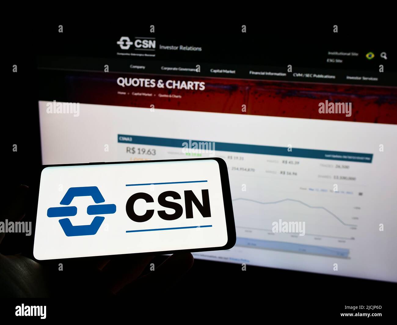 Person holding mobile phone with logo of company Companhia Siderurgica Nacional (CSN) on screen ...