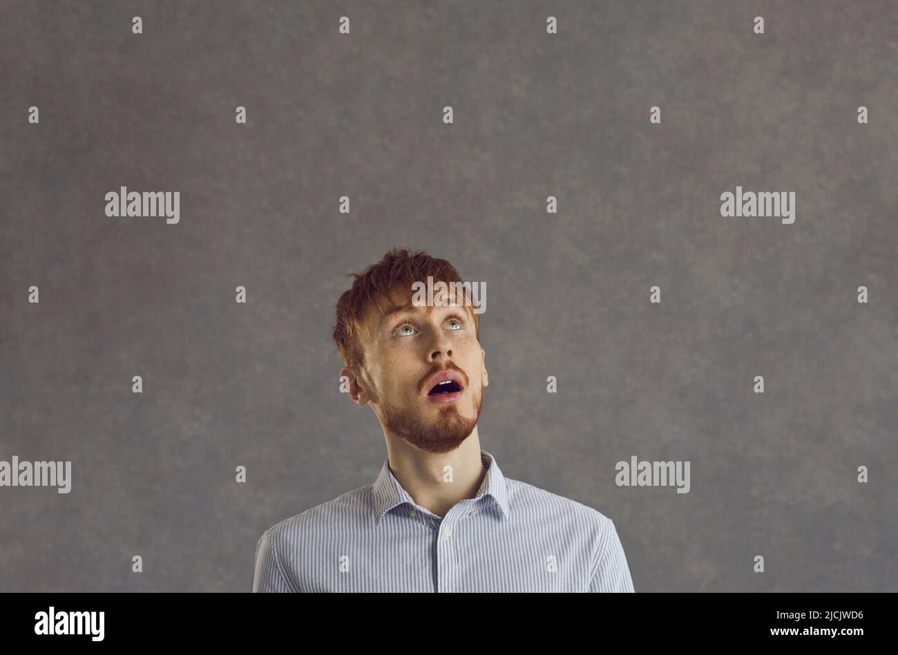 Portrait of a young man looking up at something with a surprised face ...