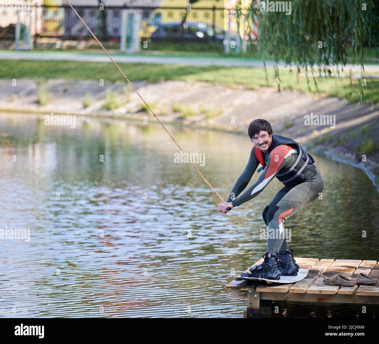 Wakeboarder getting ready to surfing on lake. Young man surfer having ...