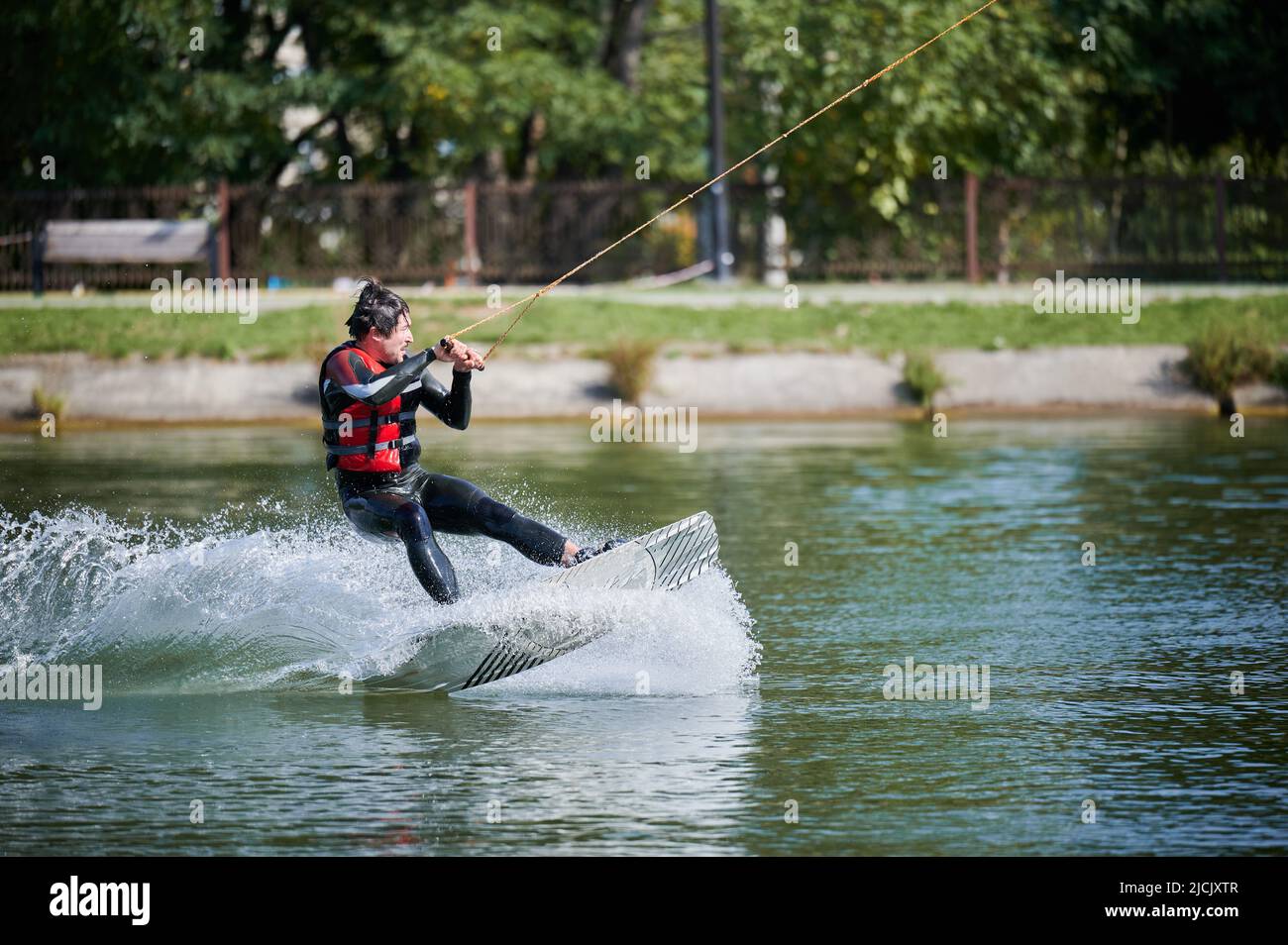 Wakeboarder surfing on lake. Young man surfer having fun wakeboarding ...