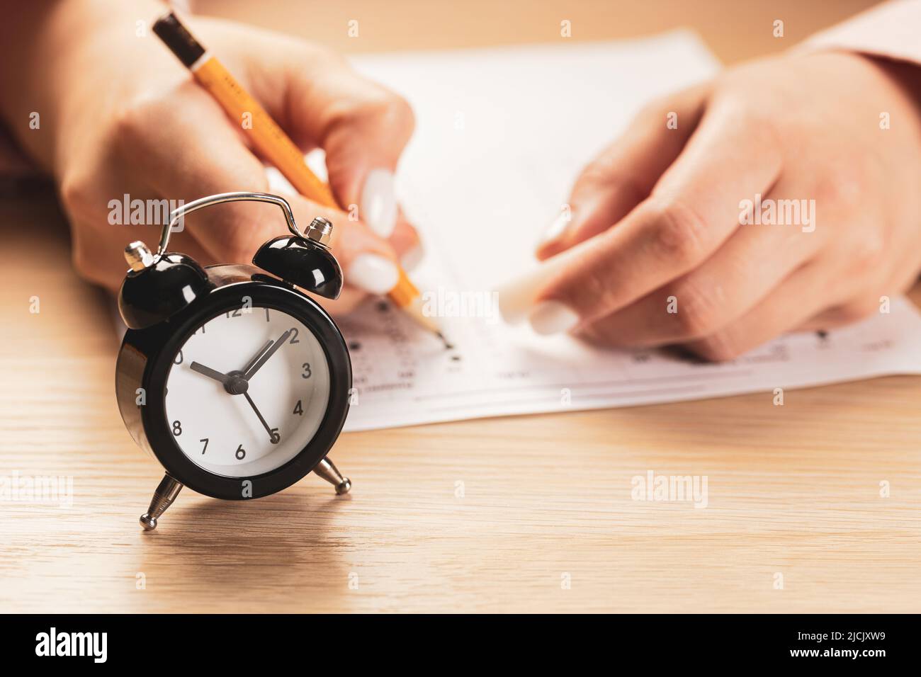 alarm clock with time running out. Students hands to take exams, write ...