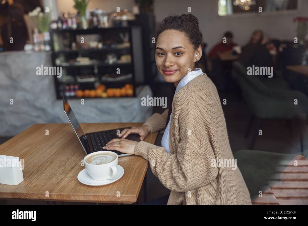 Cute African woman student blogger with laptop in cafeteria. Internet ...