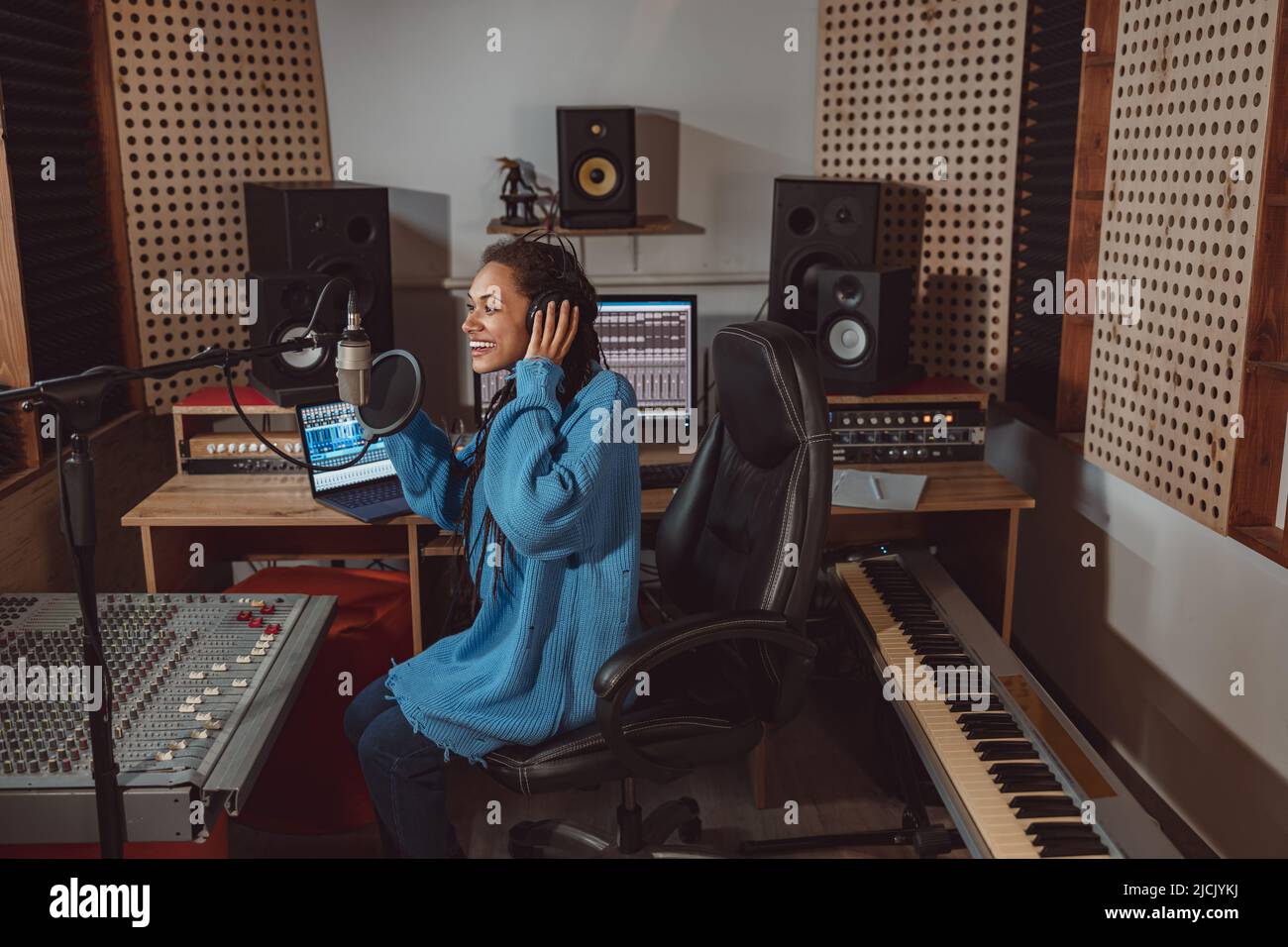 Pleasant radio presenter wearing headphones talking into professional microphone in a ...