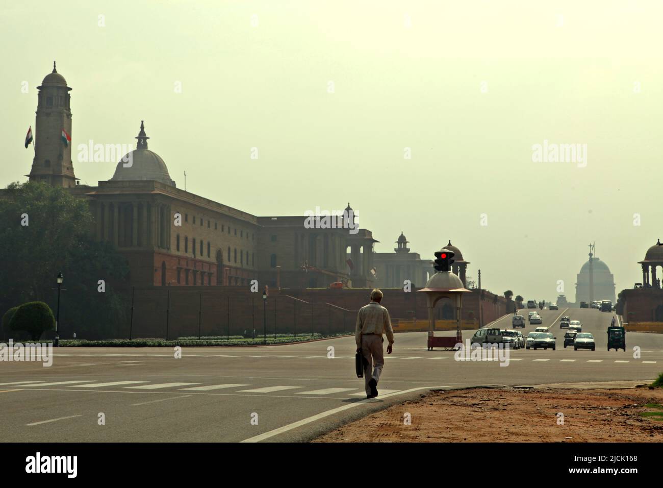 A man walking on Rajpath boulevard is photographed in a background of ...