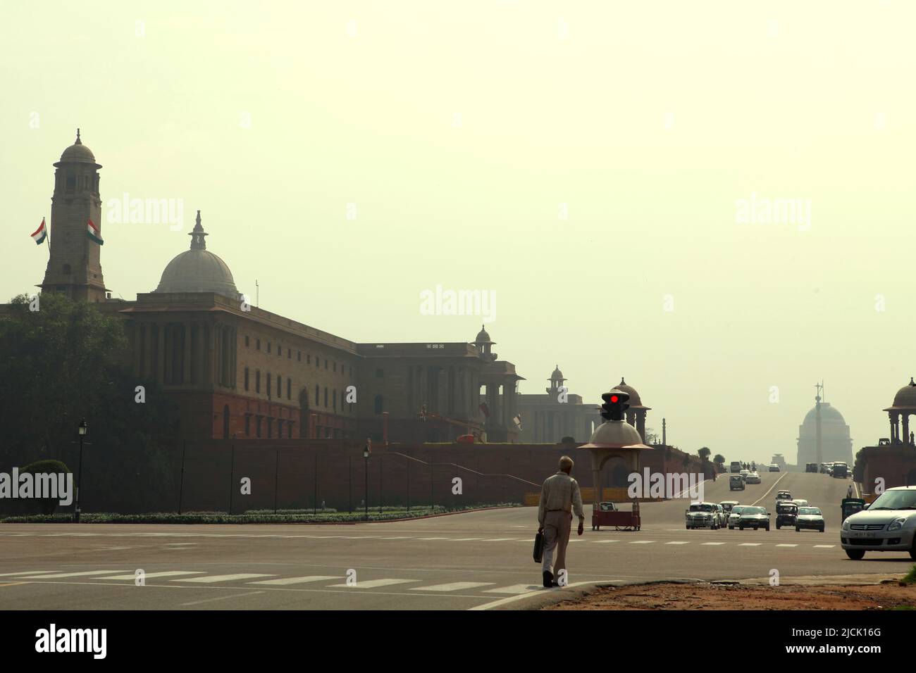 A man walking on Rajpath boulevard in a background of road traffic ...