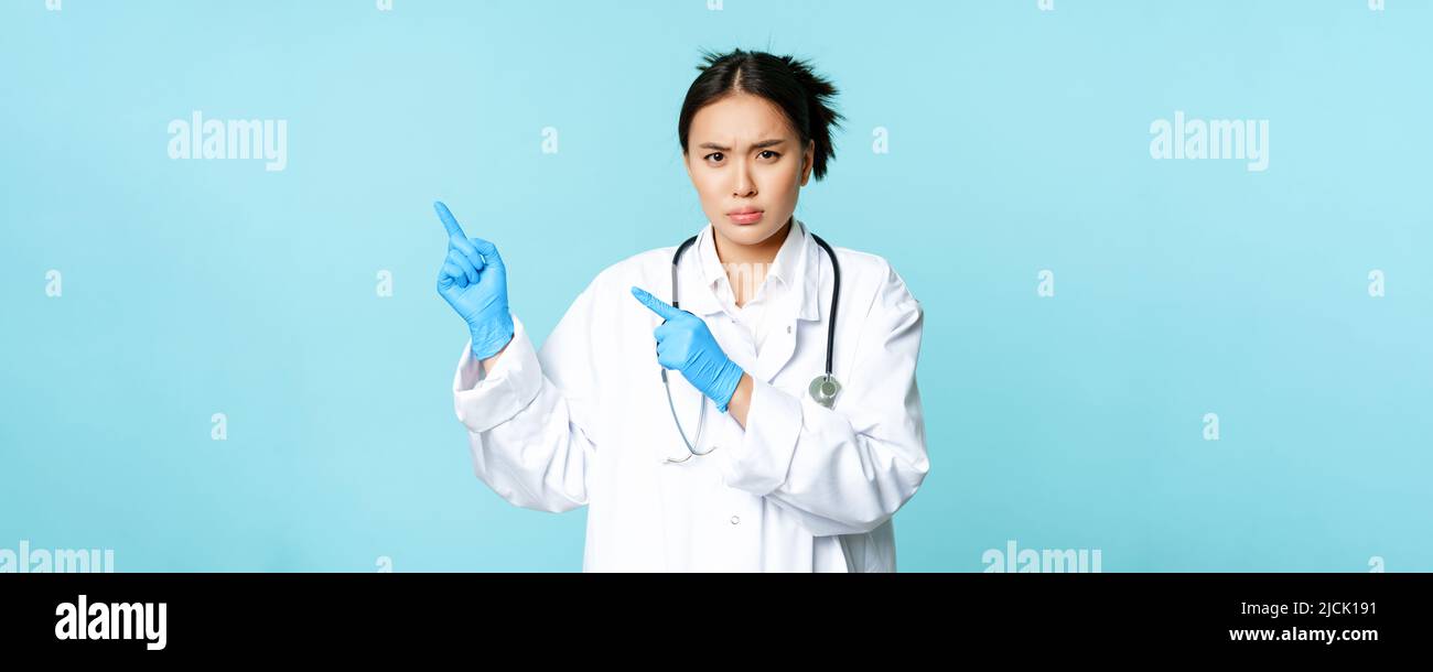 Angry female doctor or nurse, pointing fingers at upper left corner ...