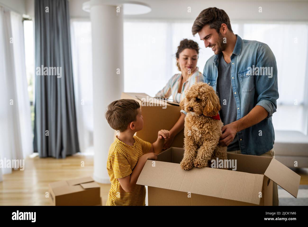 Happy family with children moving with boxes in a new apartment house ...