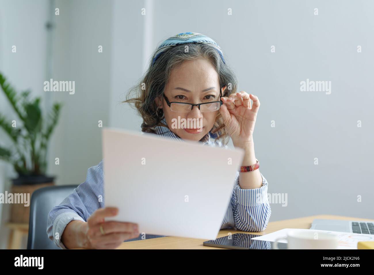 Portrait of an elderly woman holding an important document to verify ...