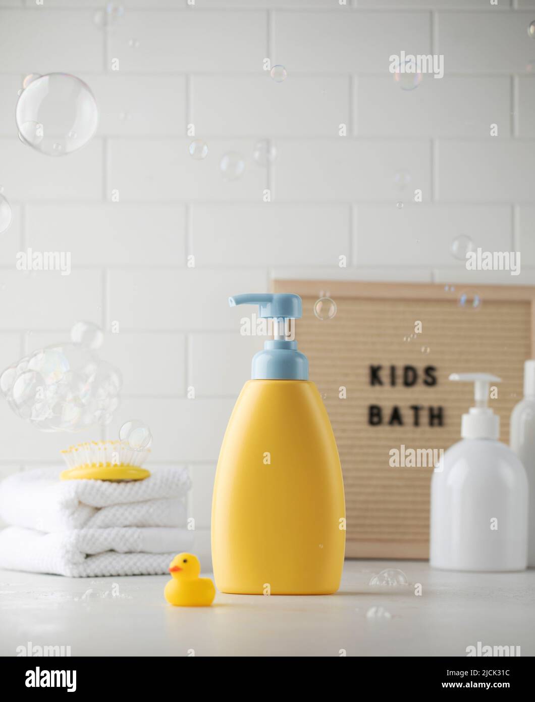 Blank bottle of children shampoo accessories and flying soap babbles in ...