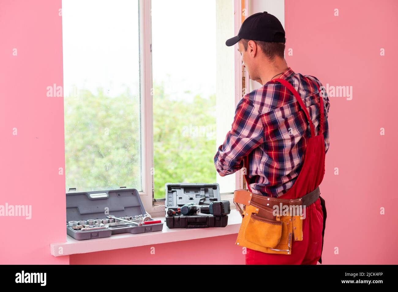 handyman adjusting white pvc plastic window indoors. worker using ...