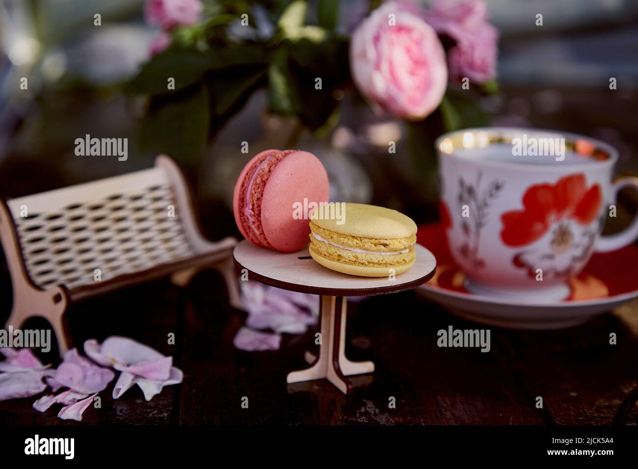 French macarons on the wooden miniature table near bench in cafe style ...