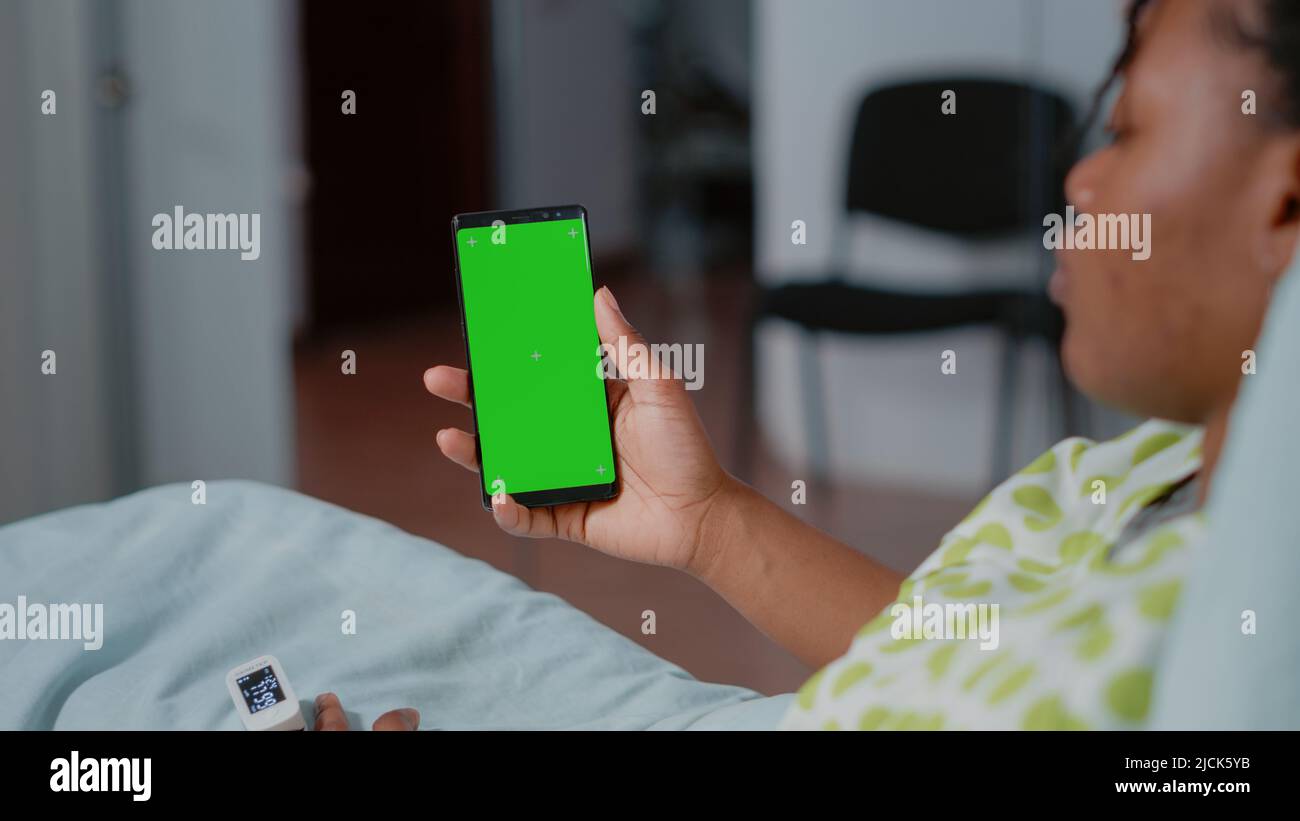 Close up of patient holding smartphone with green screen in hospital ...