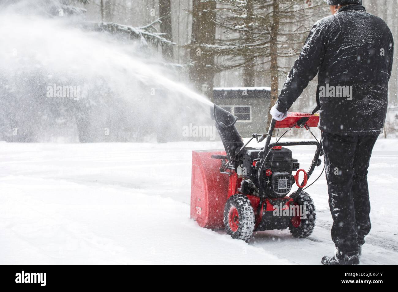 Man using snow blower machine to clear driveway at snow day Stock Photo ...