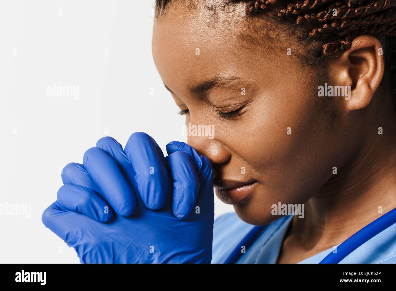 Young black doctor wearing uniform making prayer gesture isolated over ...