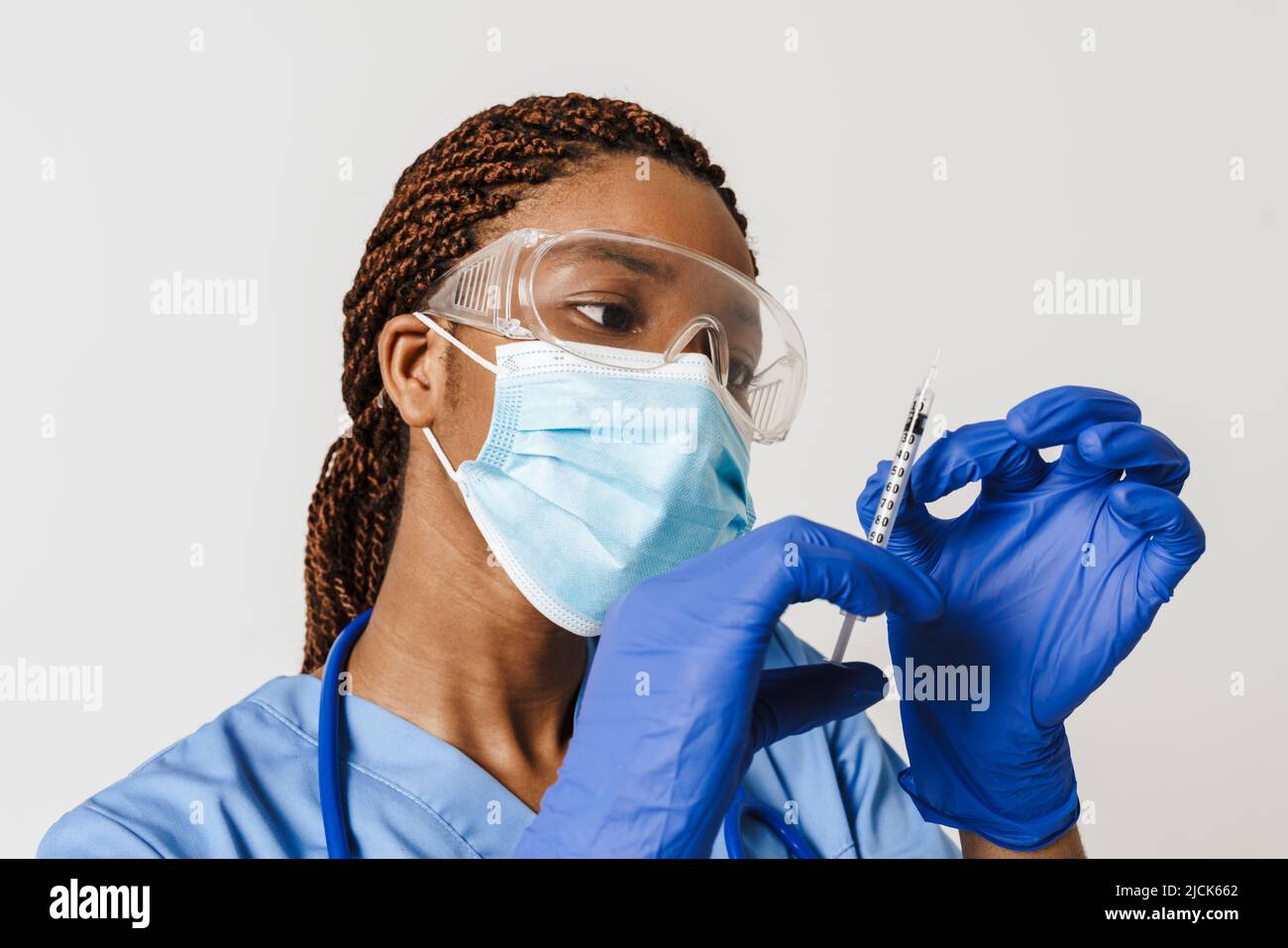 Black doctor wearing face mask posing with syringe isolated over white ...