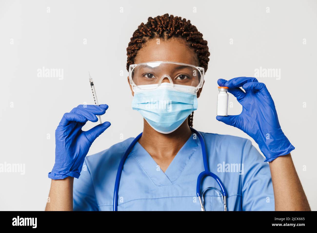 Black doctor wearing face mask posing with vaccine and syringe isolated ...