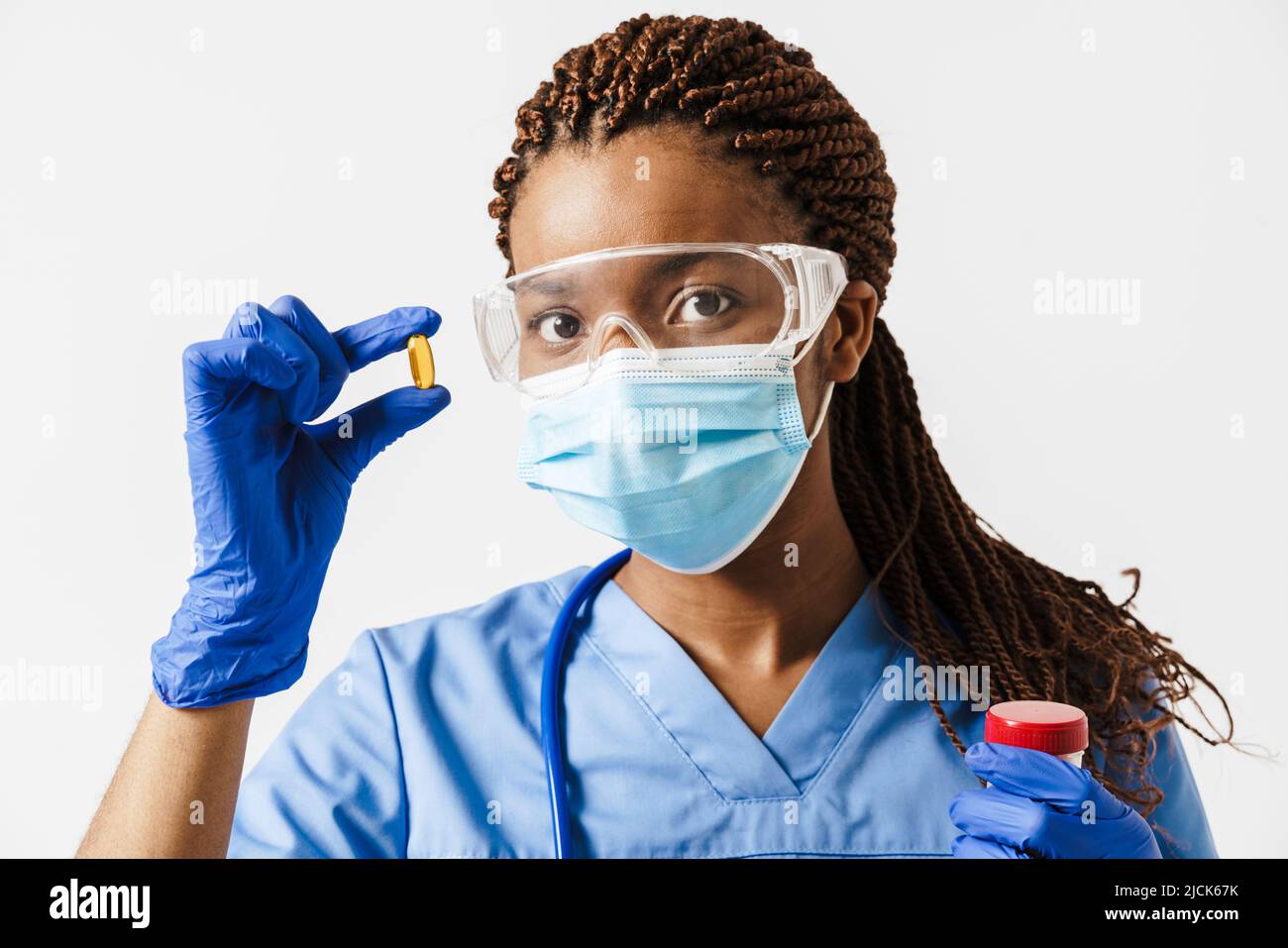 Black pregnant doctor wearing face mask showing pill isolated over ...