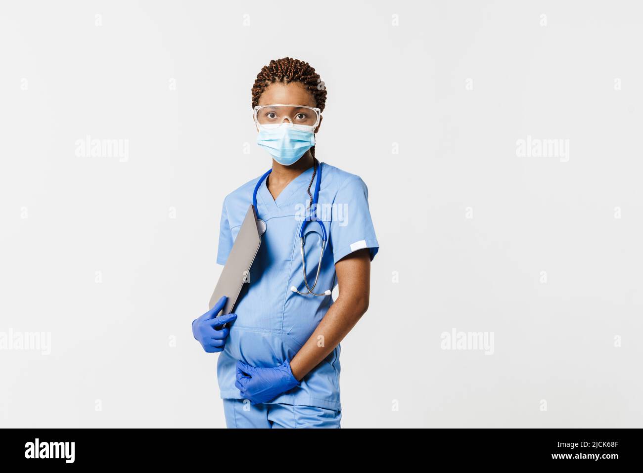 Black pregnant doctor in face mask posing with laptop isolated over ...