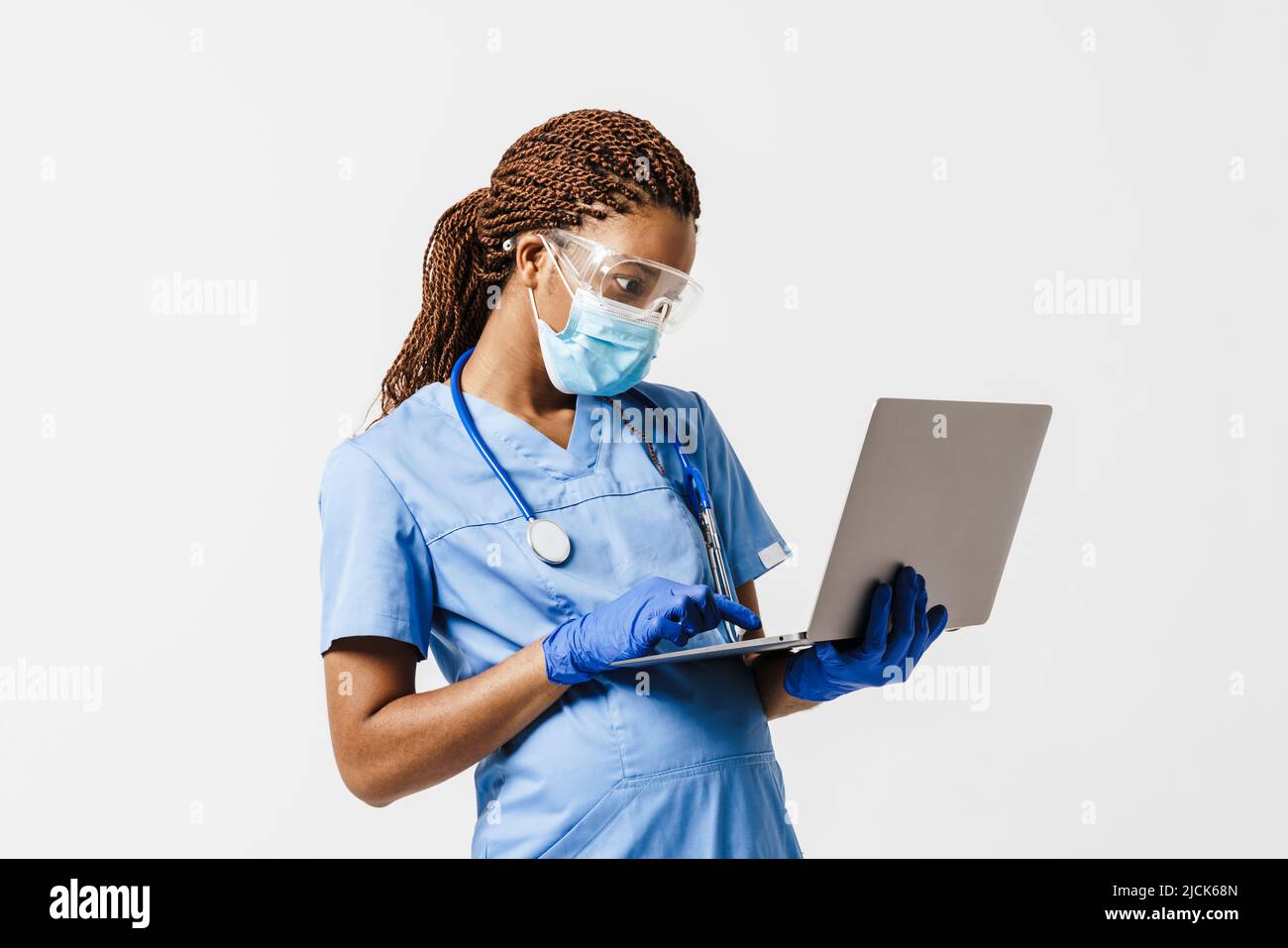 Black pregnant doctor in face mask posing with laptop isolated over ...
