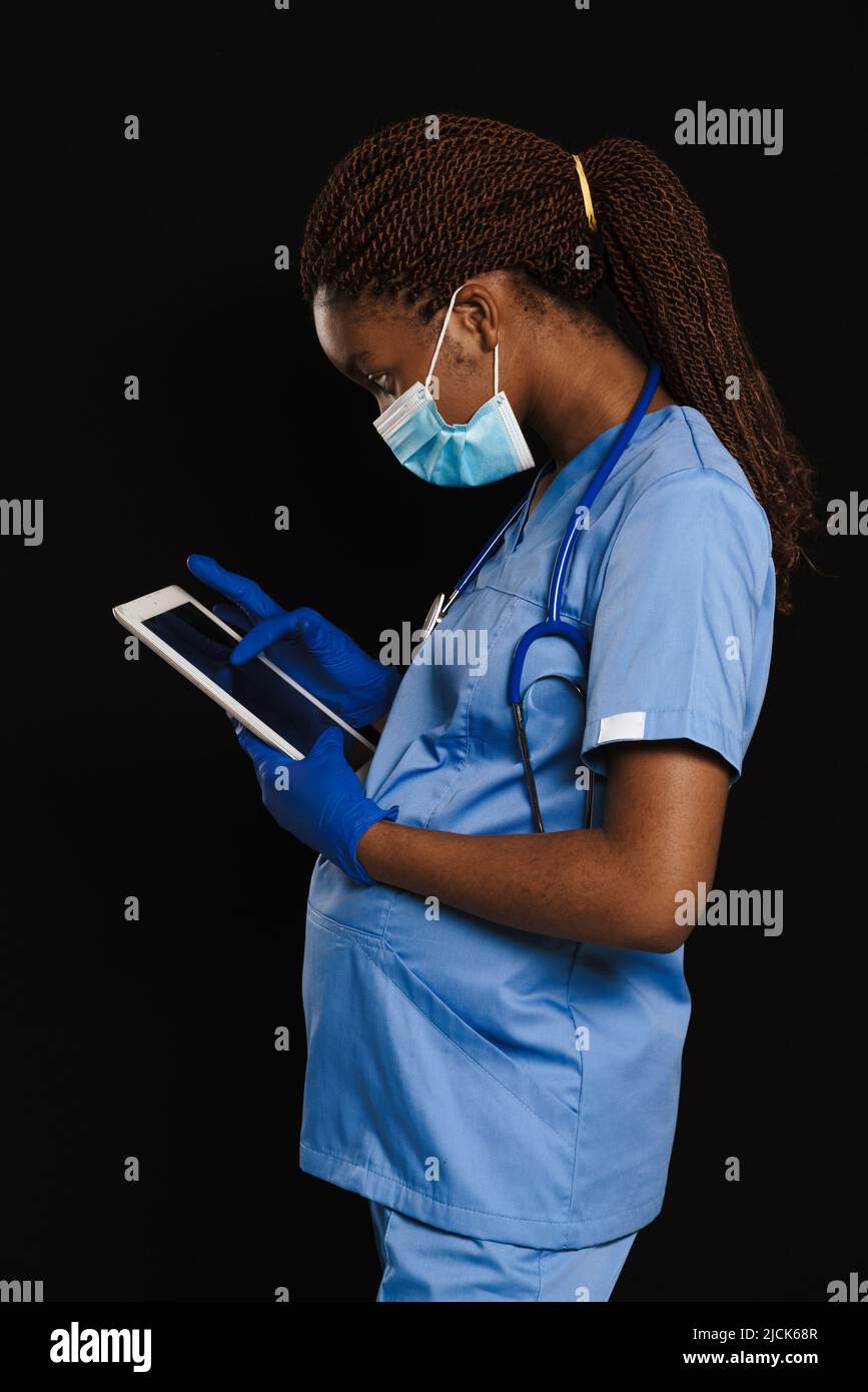 Black pregnant doctor in face mask using tablet computer isolated over ...