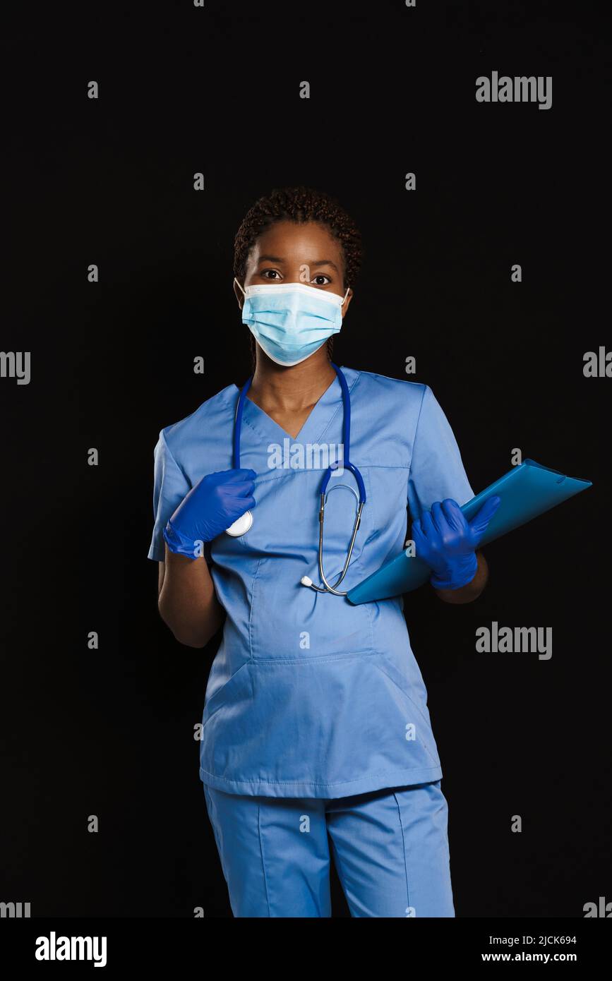 Black pregnant doctor in face mask posing with folder isolated over ...