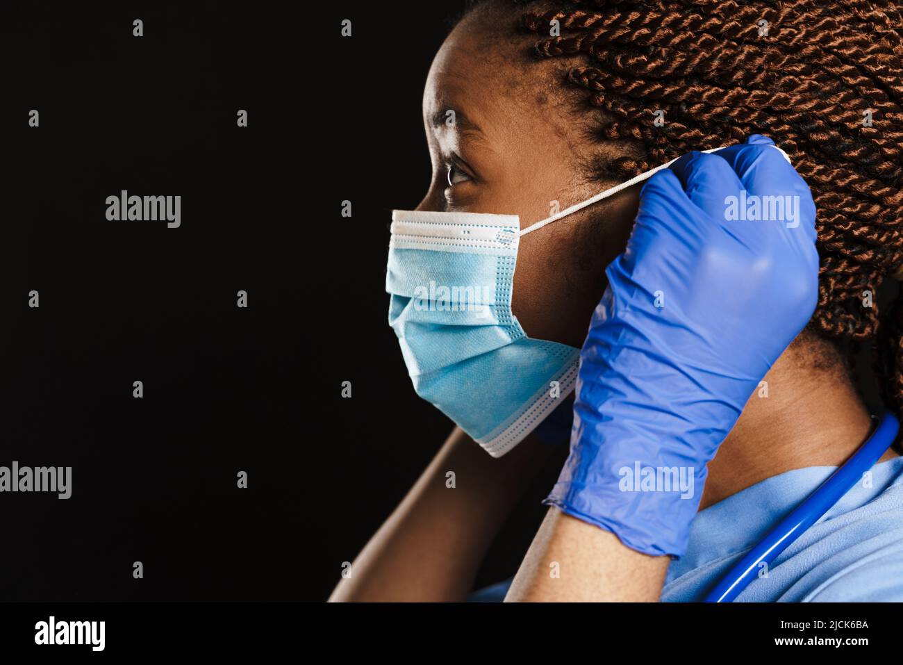 Black doctor wearing face mask and gloves looking aside isolated over ...