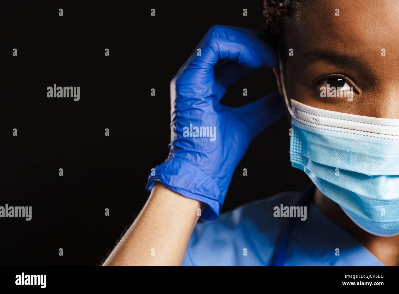 Black doctor wearing face mask and gloves looking at camera isolated ...