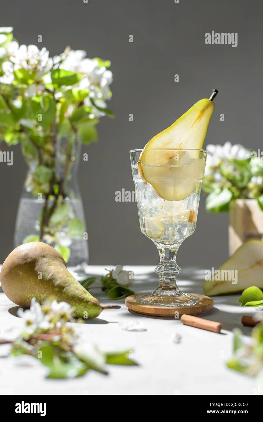 Pear cocktail with pear puree and fresh fruit and flowers on light gray ...