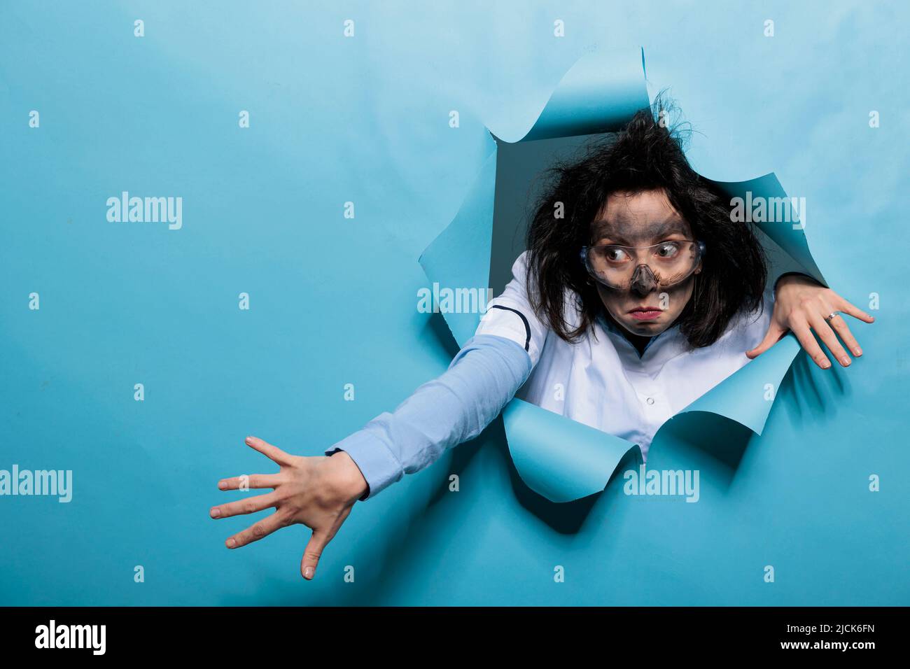 Young adult chemist with wacky look, messy hair and dirty face acting ...
