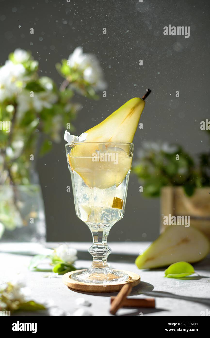 Pear cocktail with pear puree and fresh fruit and flowers on light gray ...