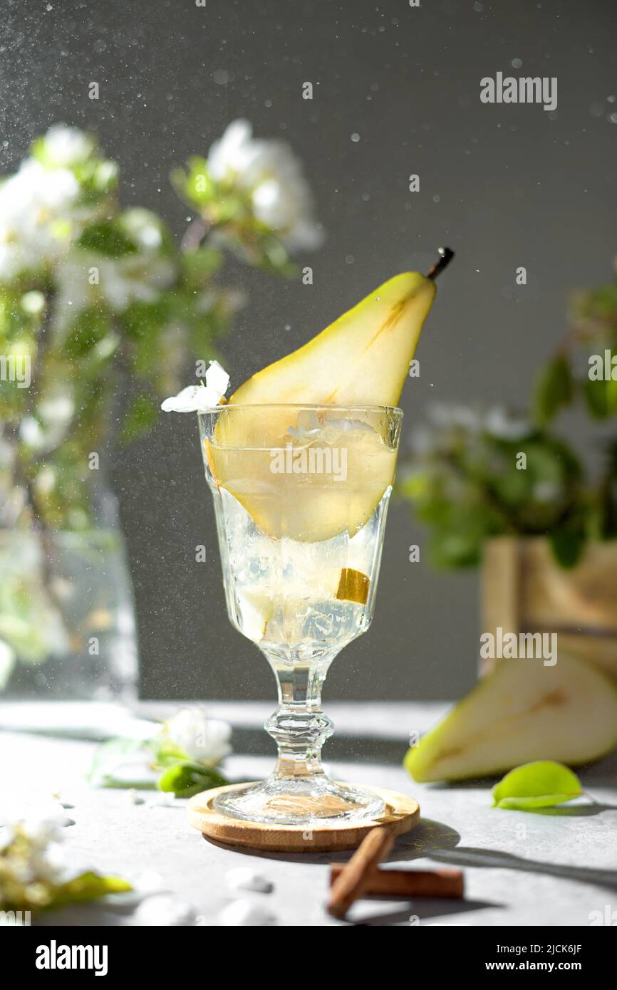 Pear cocktail with pear puree and fresh fruit and flowers on light gray ...