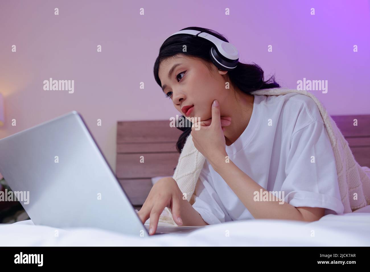 Young Asian blogger in headphones editing video on laptop, adding music ... Young Asian blogger in headphones editing video on laptop, adding music ...