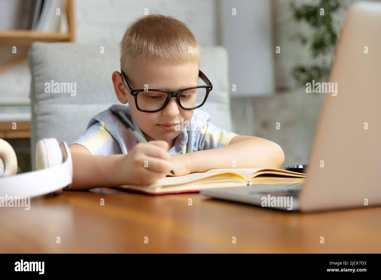 Little boy, school age kid doing homework, using laptop at home ...
