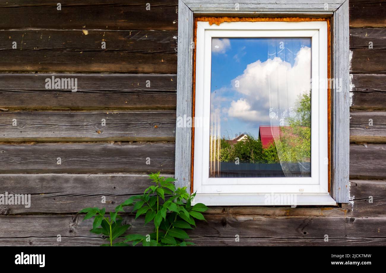 Background. Window in a wooden house. Reflection of the blue sky and ...