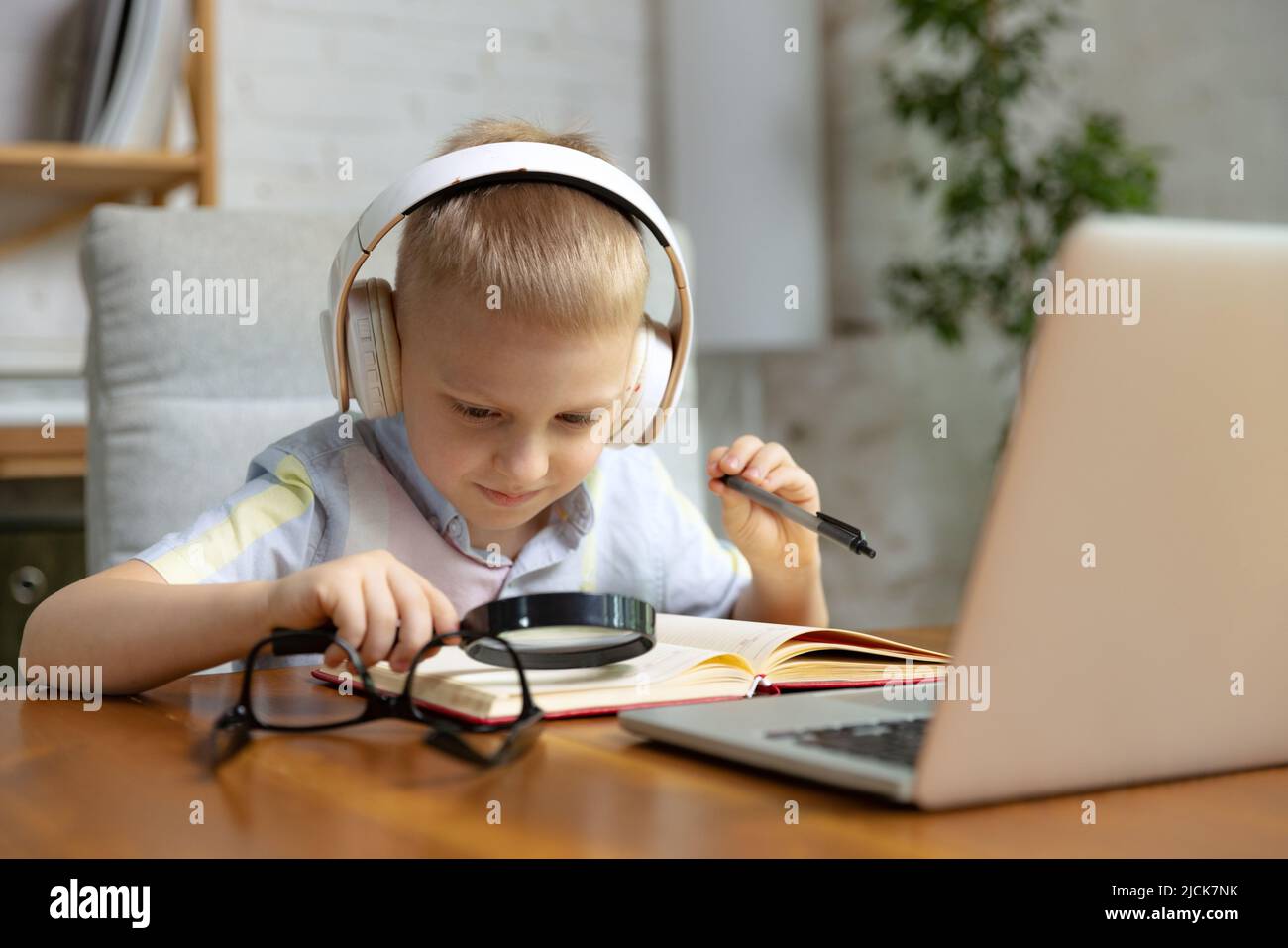 Little boy, school age kid doing homework, using laptop at home ...