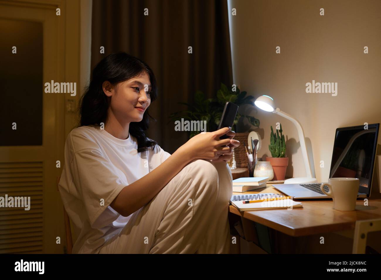 Positive Vietnamese teenage girl texting friends instead of doing ...