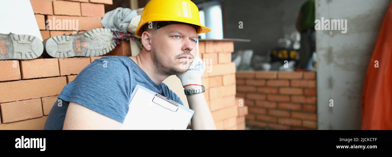 Upset worker sit surrounded with construction site mess with paper ...