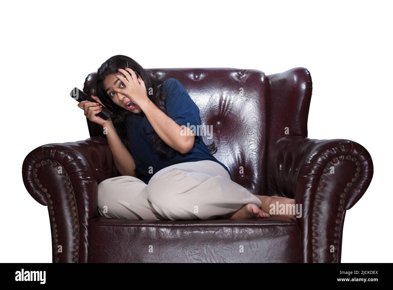 Asian woman holding a television remote sitting on the couch with a ...