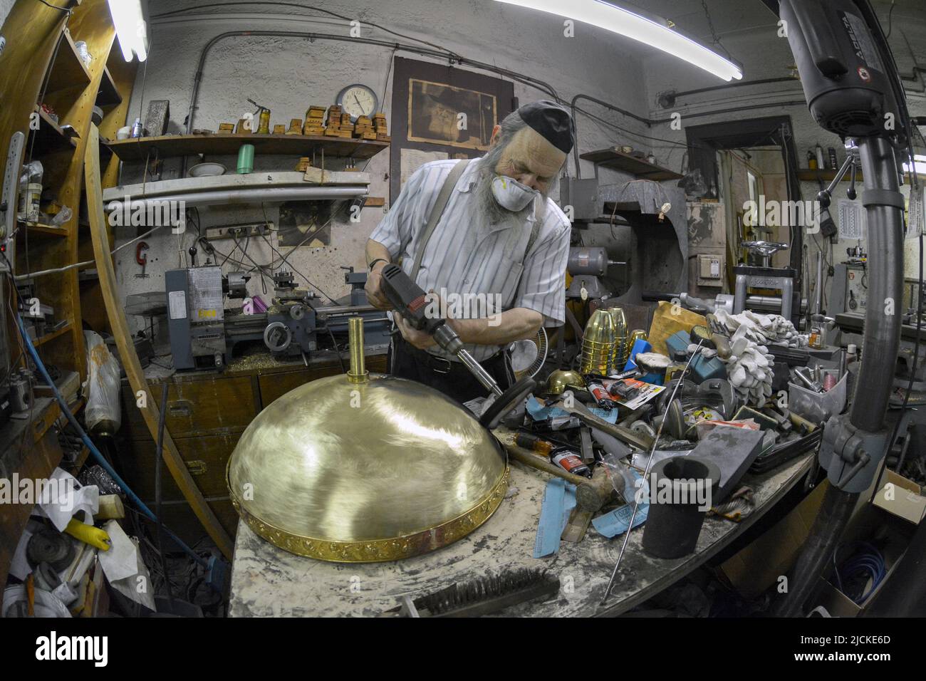 A Jewish silversmith and master craftsman works polishing the base of a ...