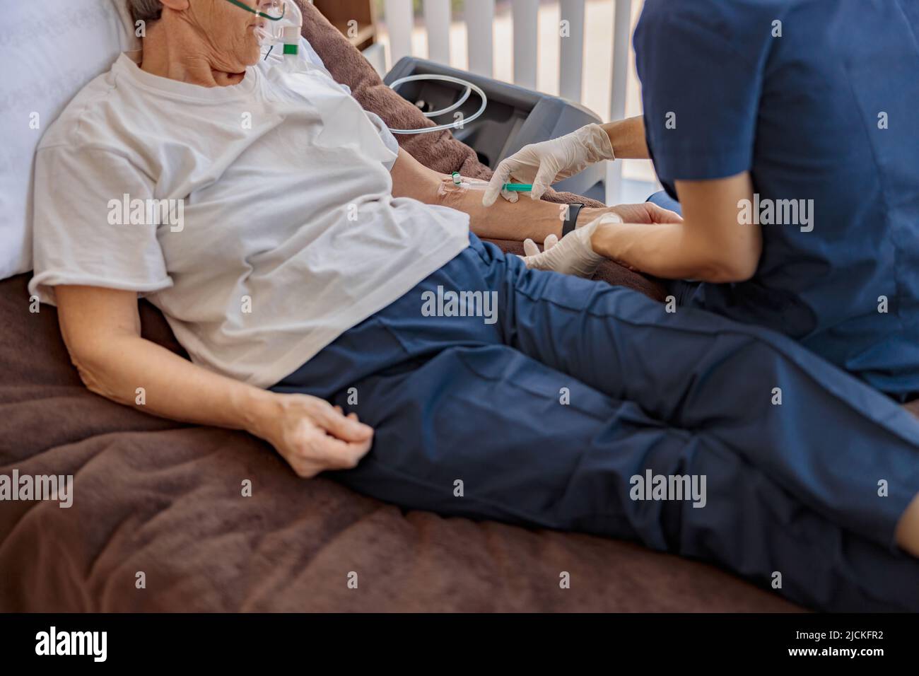 Nurse putting a drip on the arm of her patient in mask during pandemic ...