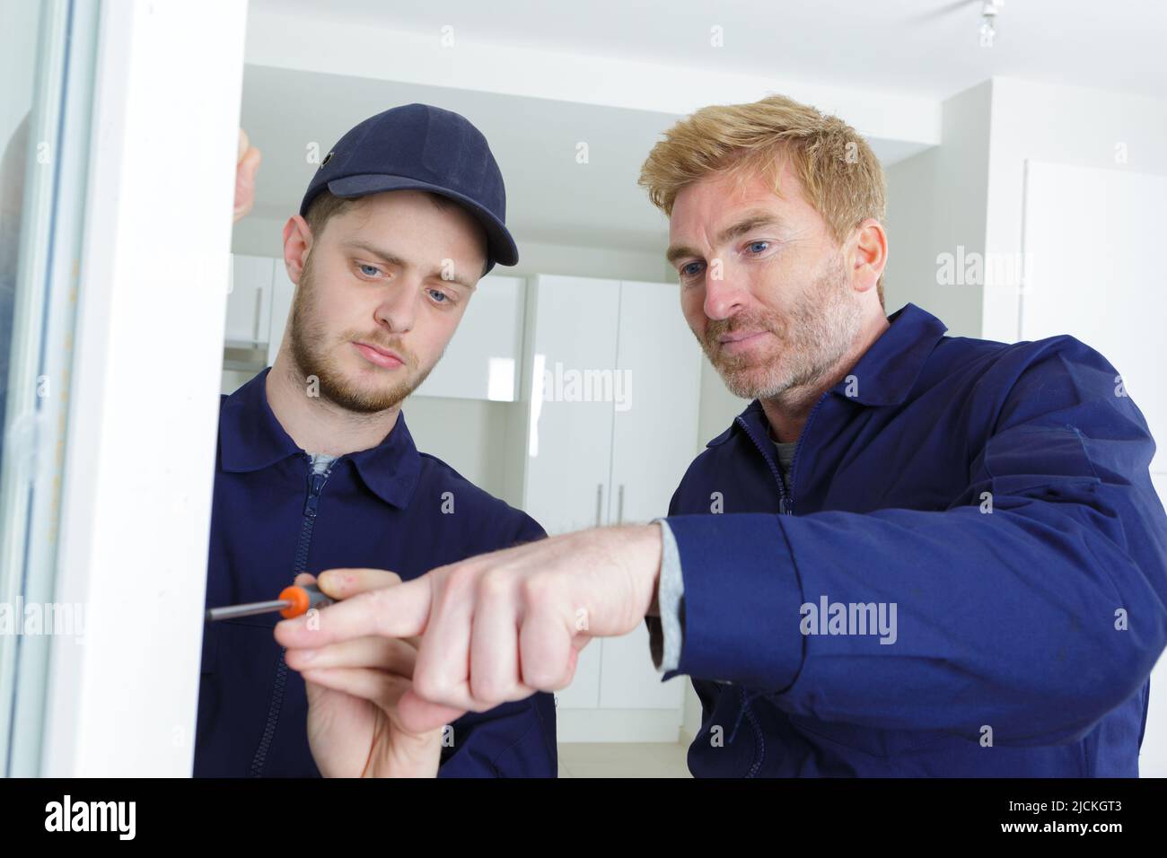 contractor and apprentice fixing door lock Stock Photo - Alamy