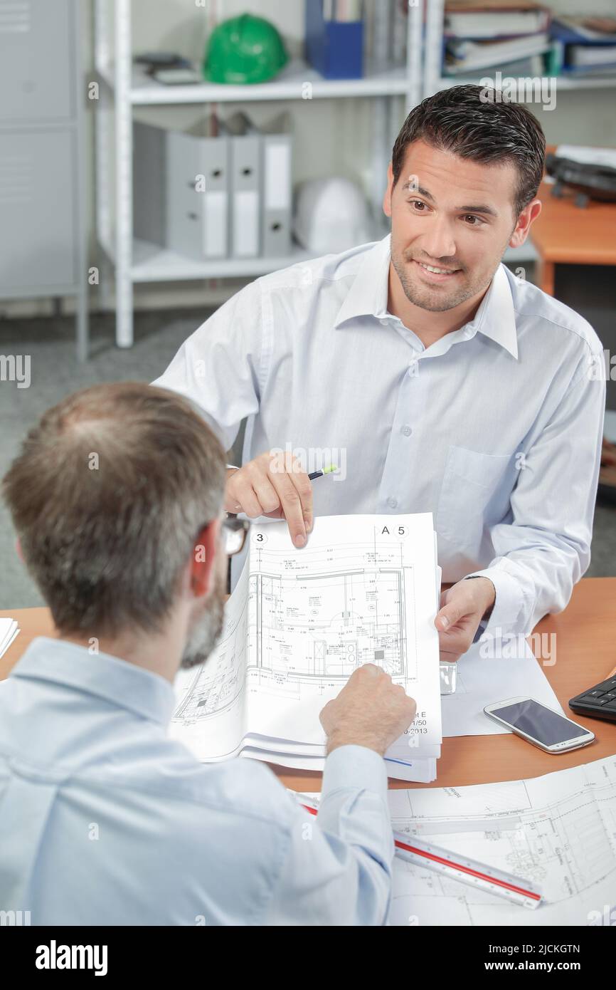Two men in meeting looking at blueprints Stock Photo - Alamy