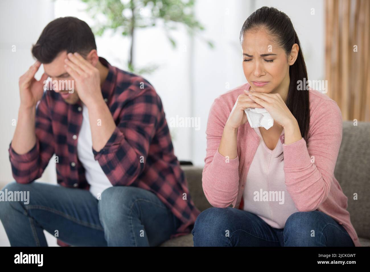 emotional man and woman sat not speaking on the sofa Stock Photo - Alamy