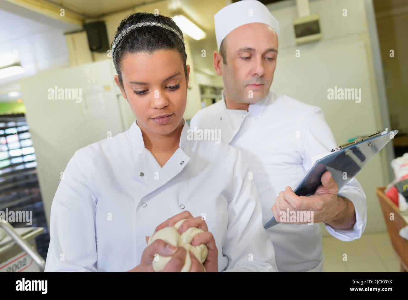 apprentice chef working dough supervisor with clipboard watching over ...