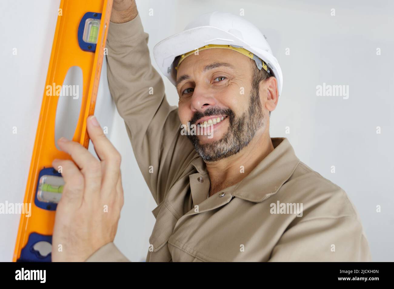 builder in helmet is measuring wall with level Stock Photo - Alamy
