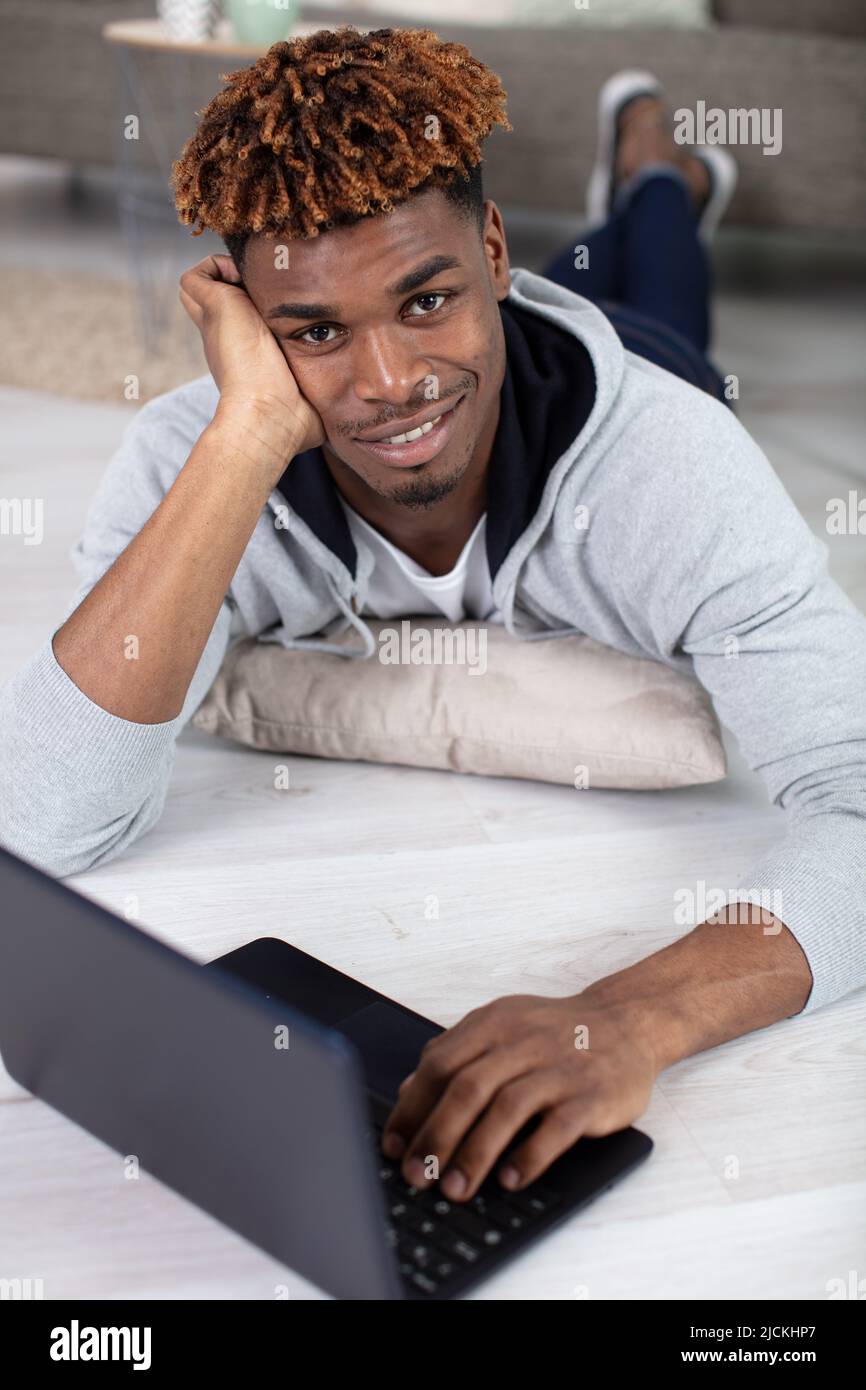 attractive smiling chill guy is browsing at his laptop Stock Photo - Alamy