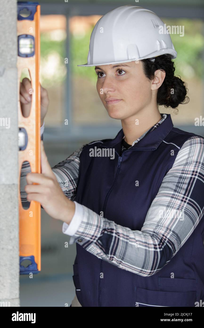 concentrated woman using a level on the wall Stock Photo - Alamy