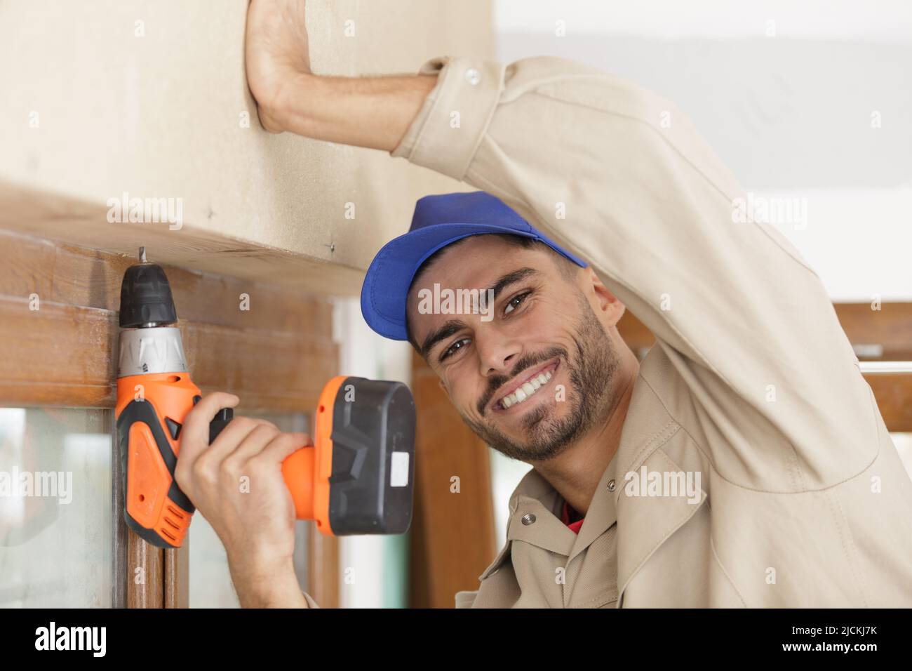 happy man drilling a hole in a window frame Stock Photo - Alamy