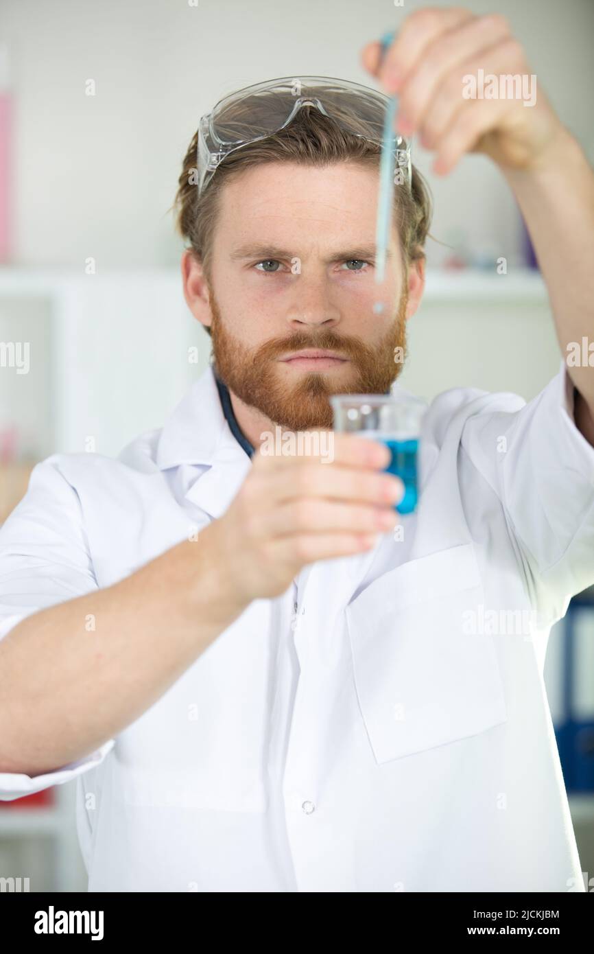 male scientist dropping liquid into a beaker Stock Photo - Alamy